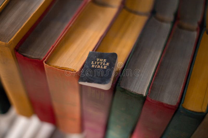 The Small Holy Book of the Bible Lies on Large Multi-colored Books ...