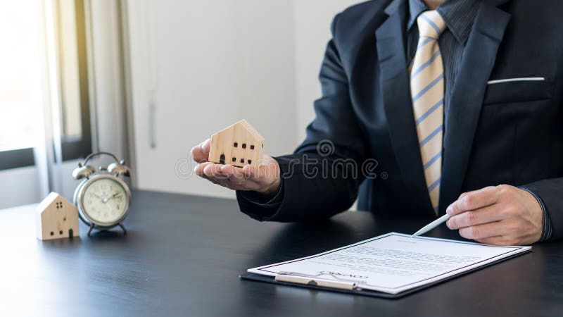 A Small House Model in the Hands of a Real Estate Agent and Left Hand ...