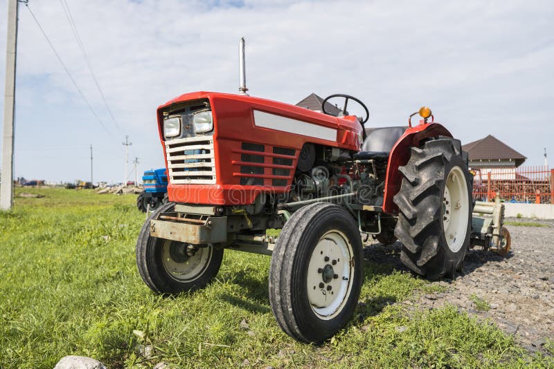 A Small Mini Red Tractor Stands on a Farm Yard on Green Grass and Waits ...