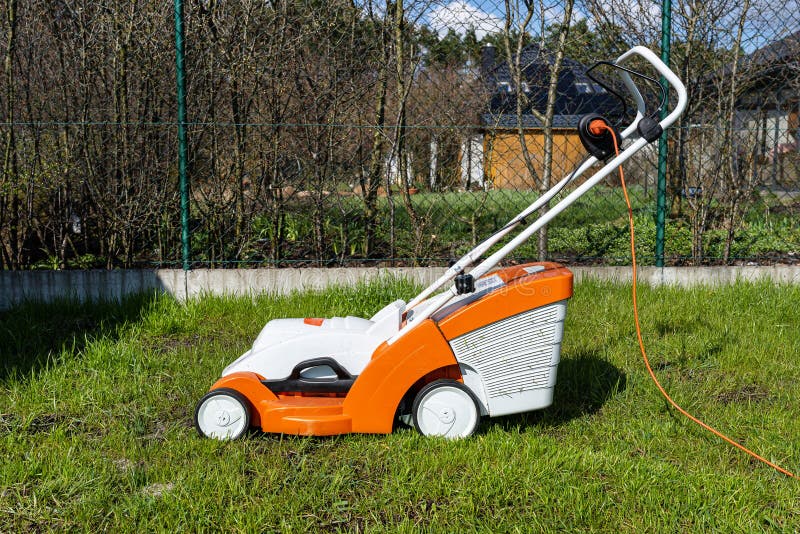 A Small Motorized Electric Mower Standing on the Lawn, it is Orange in ...