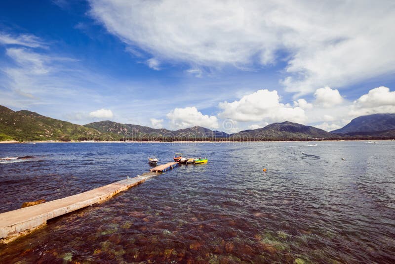 A Small Pier for Boats on a Clear Water on a Background the Mountains ...