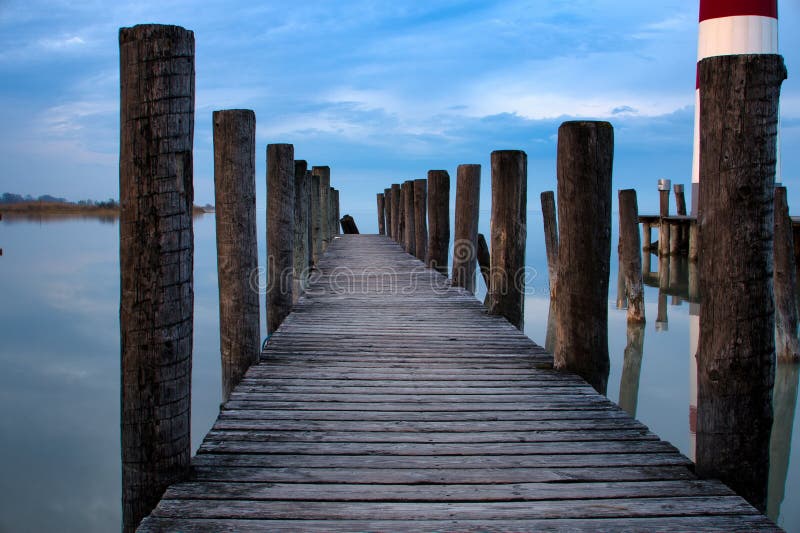 A Small Pier is Lined with Posts and a Red and White Lighthouse Stock ...