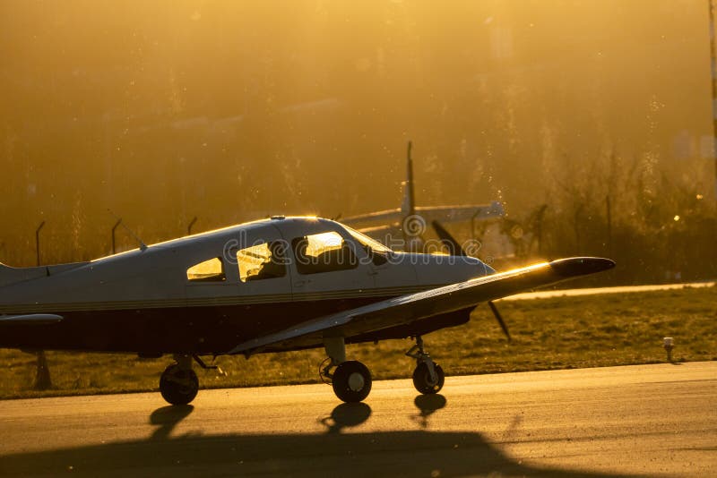 A Small Propeller Plane Rolling Down the Runway in Backlight Under a ...