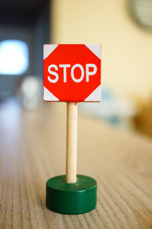 Small Red Stop Sign on a Wooden Table Under the Lights with a Blurry ...