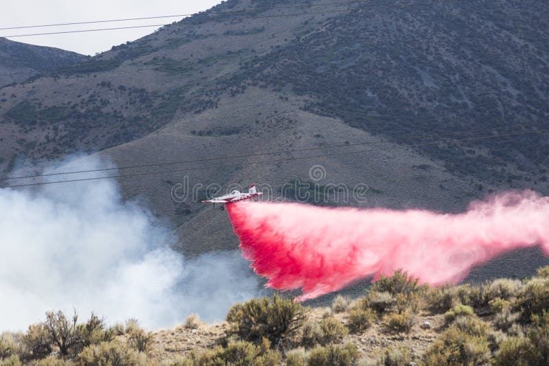 Small Red and White Plane Drops Fire Retardant on a Fire in a Valley ...