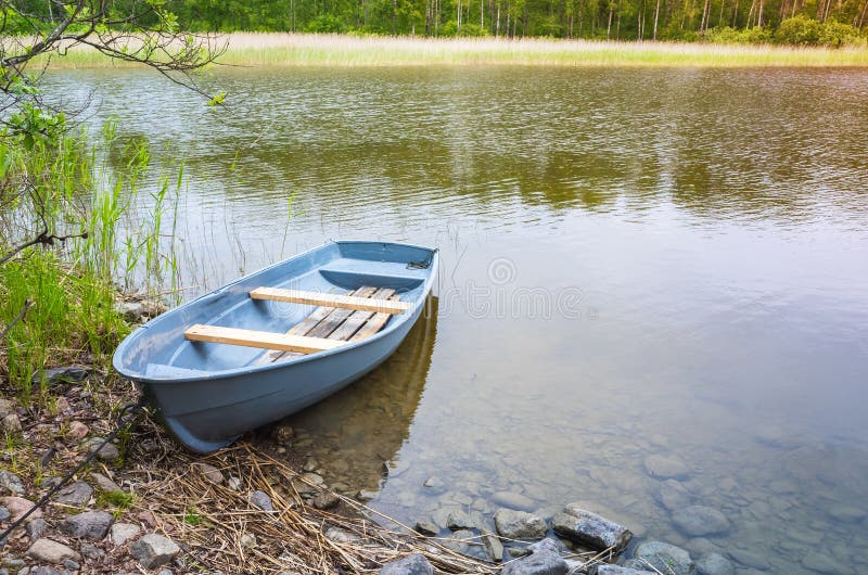 Small Rowboat Lays on Coast of Still Lake Stock Photo - Image of rope ...