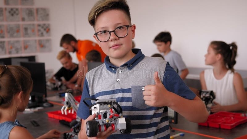 A Small Smart Boy Holds a Robot in His Hands in the Robotics Office ...