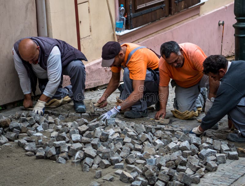 Team of Construction Workers Building Pavement with Cobblestones ...