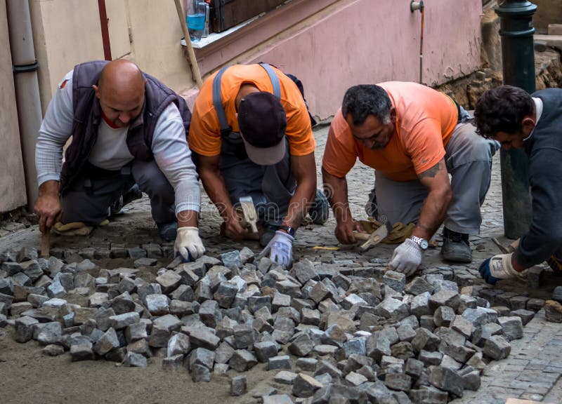 Team of Construction Workers Building Pavement with Cobblestones ...