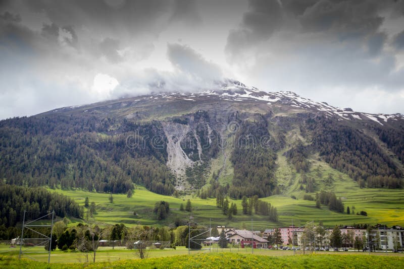 Small Town in Alps Valley. Dramatic Looking Sky with Eye Catching Green ...