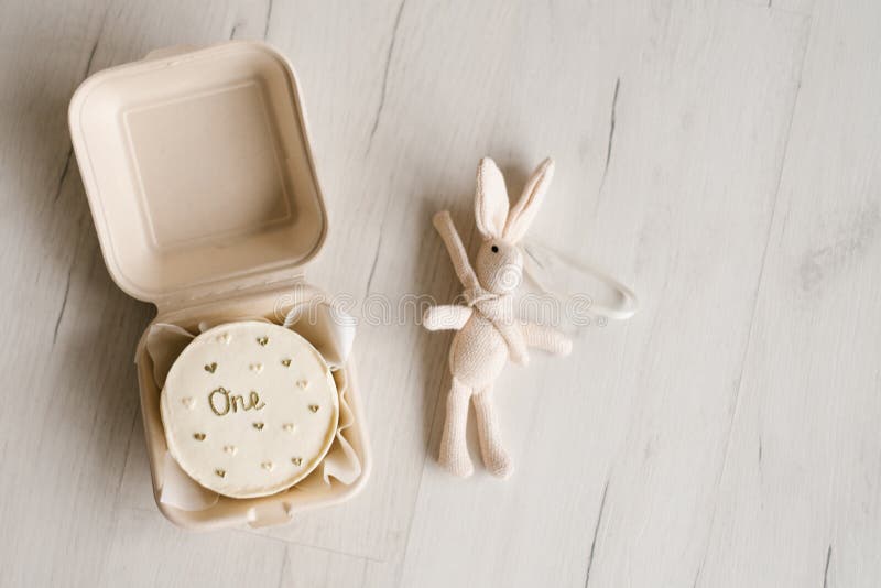 Small Toy Rabbit is Sitting on a White Surface Next To a Container with ...