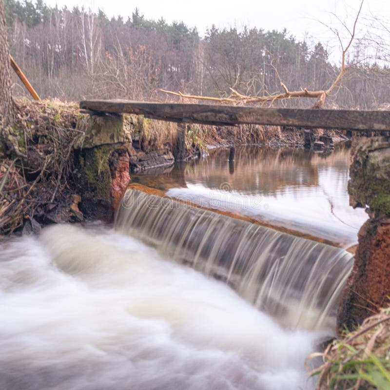 A Small Waterfall and a Bridge on a Mountain River, the Sun Shines ...