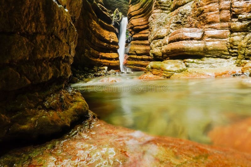 Small Waterfall and Flowing Water in the Red Canyon with Layers of Red ...
