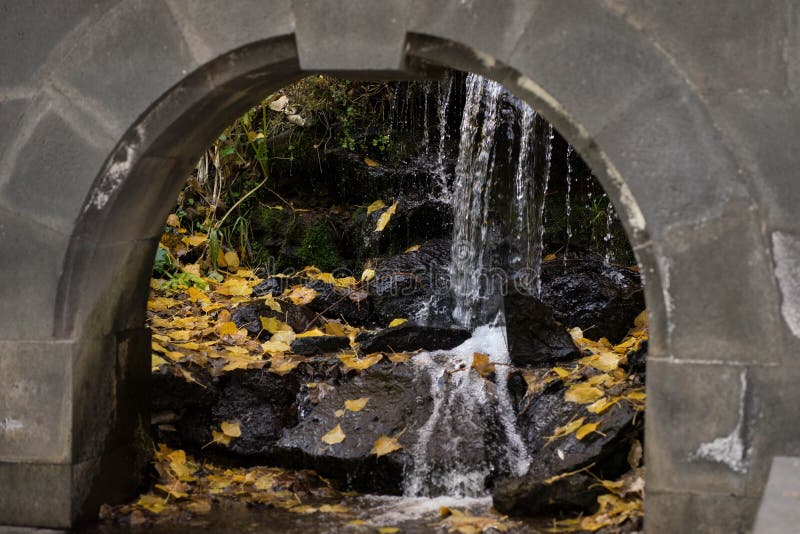 A Small Waterfall Flows through an Arch through Foliage Stock Image ...