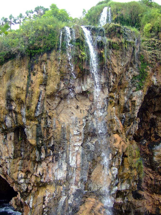 A Small Waterfall Flows Down the Stone Cliff. Top of the Cliff Green ...