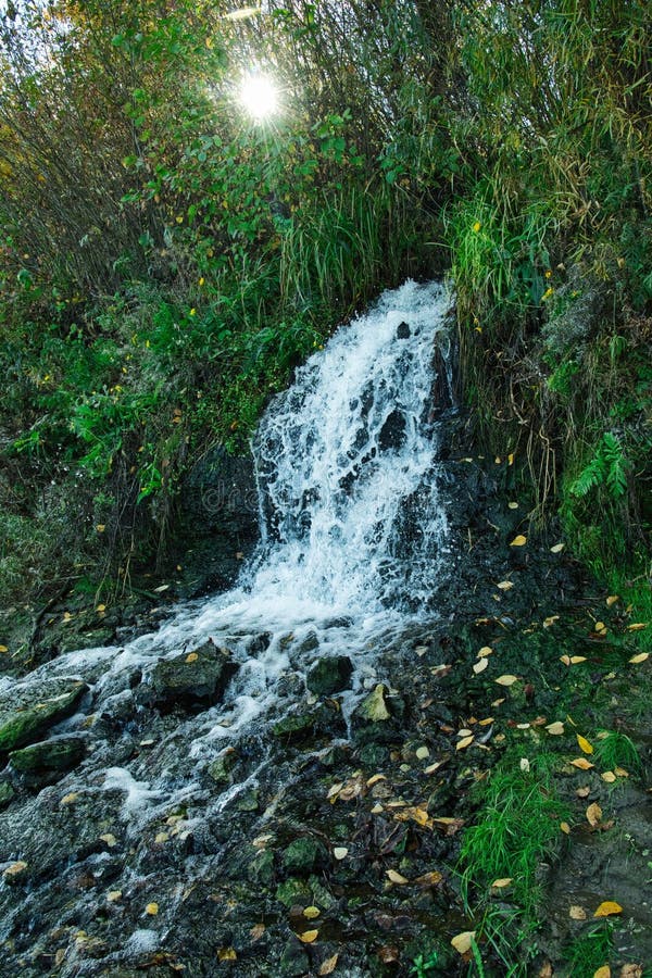 A Small Waterfall Outlet with the Sun Breakingvthrough the Trees ...