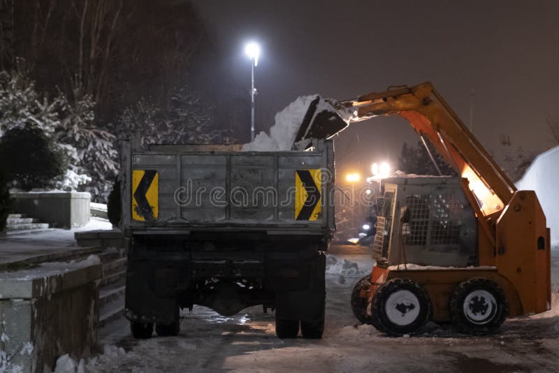 Small Wheel Loader is Unloading Snow into a Dump Truck. Stock Photo ...