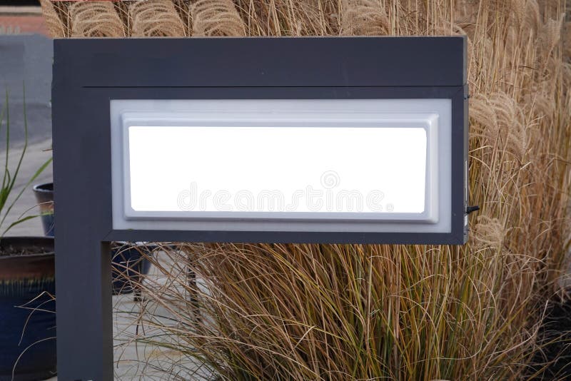 Small White Blank Illuminated Sign on a Gray Post Near a Bush Stock ...