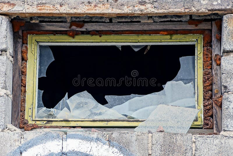 A Small Window with Broken Pieces of Glass on a Brick Building Stock ...