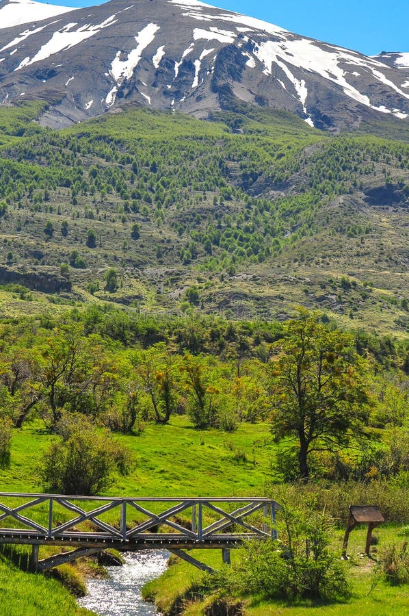 Small Wooden Bridge Over a Small River with Mountains in the Background ...