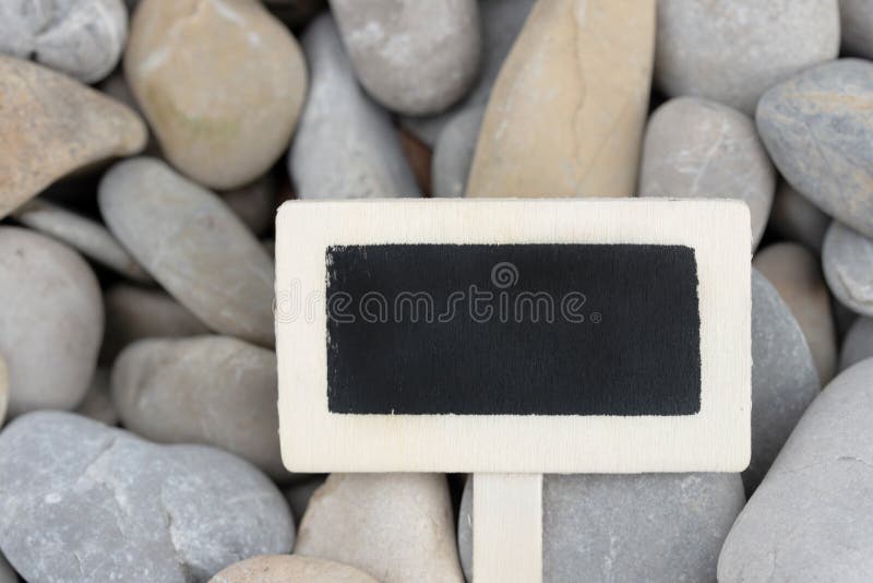 A Small Wooden Sign with a Black Writing Surface in Front of Gray ...