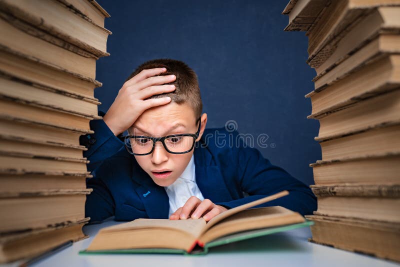 Smart Boy in Glasses Sitting between Two Piles of Books and Read Stock ...