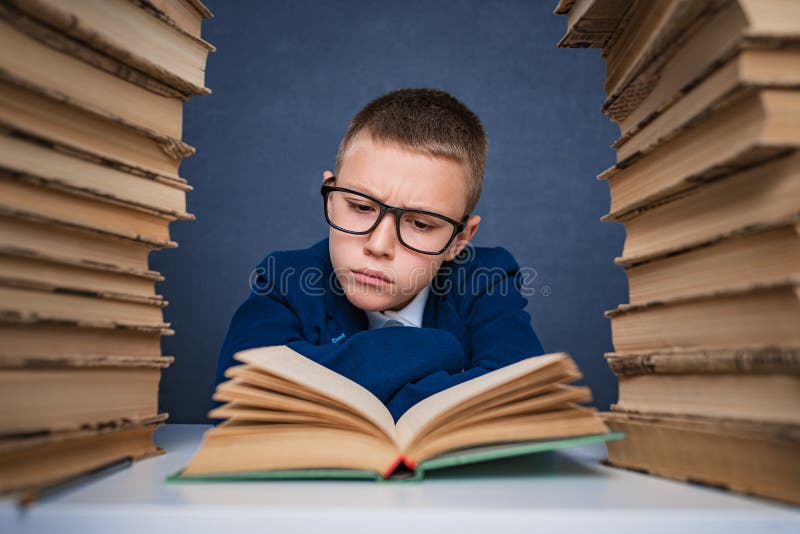 Smart Boy in Glasses Sitting between Two Piles of Books and Read Stock ...