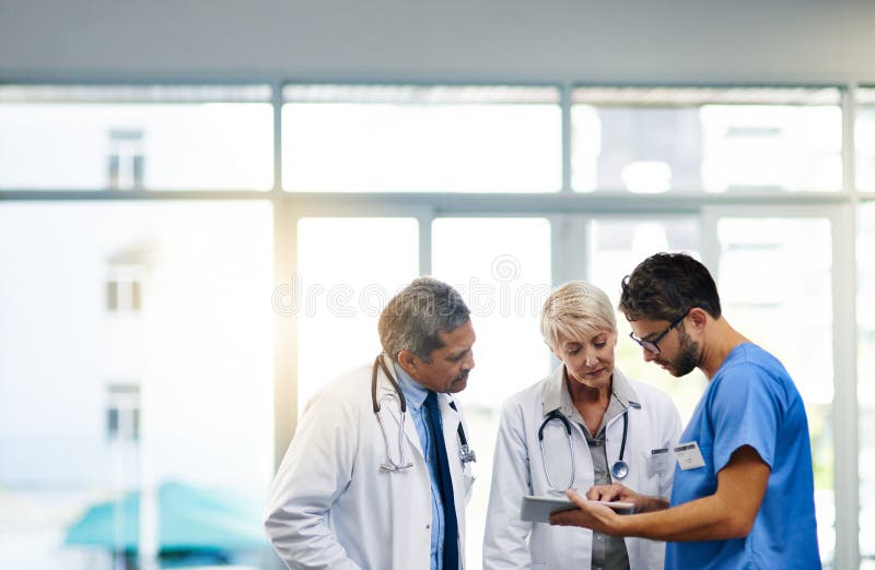 Smart Doctors Use Smart Apps. Shot of a Team of Doctors Using a Digital ...
