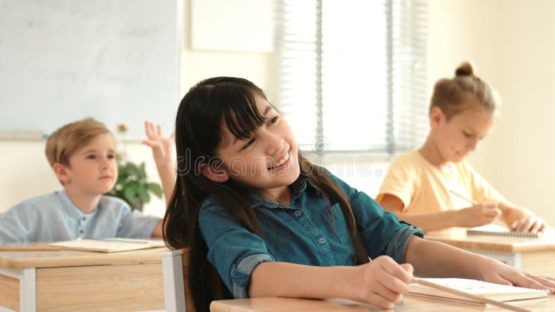 Smart Elementary Student Looking at Teacher while Attend in Classroom ...