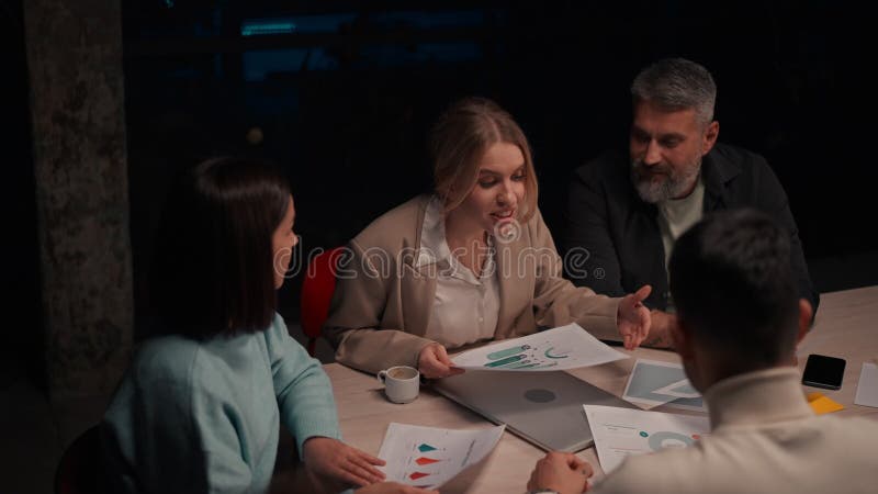 Smart Employees Discussing Documentation at Table in a Modern Evening Office at a Meeting Room ...