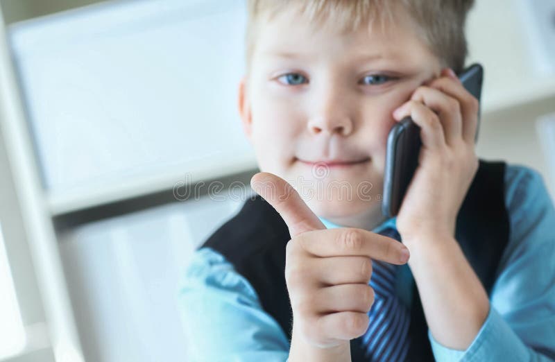 Smart Little Boy in Suit Working on Computer, Taking Notes and Speaking ...