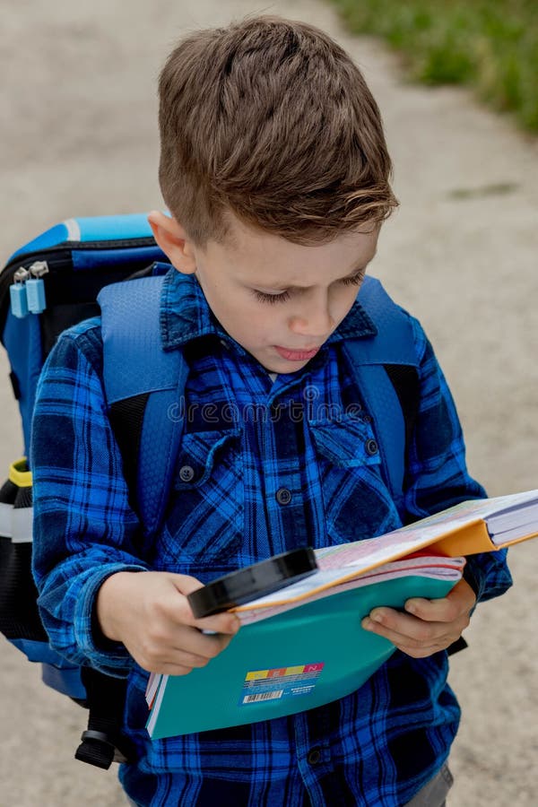 A Smart Little Student with a Magnifying Glass Reads a Textbook ...