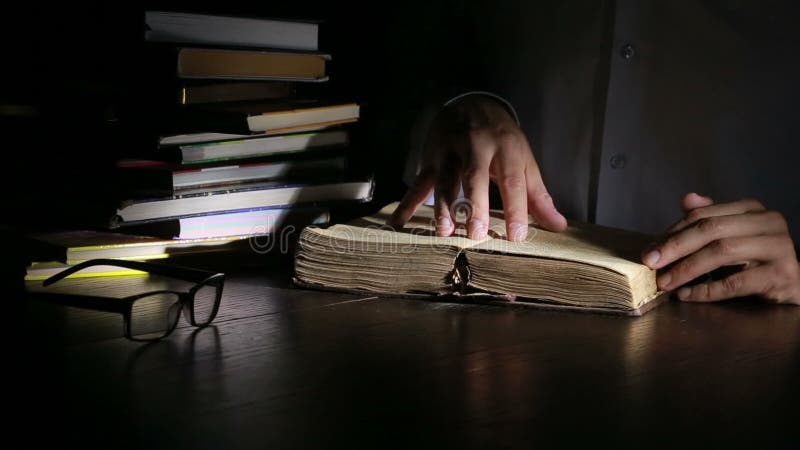 Smart Man Studying Late at Night, he is Sitting at Desk and Reading ...