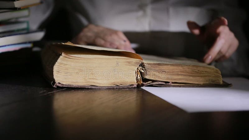 Smart Man Studying Late at Night, he is Sitting at Desk and Reading ...