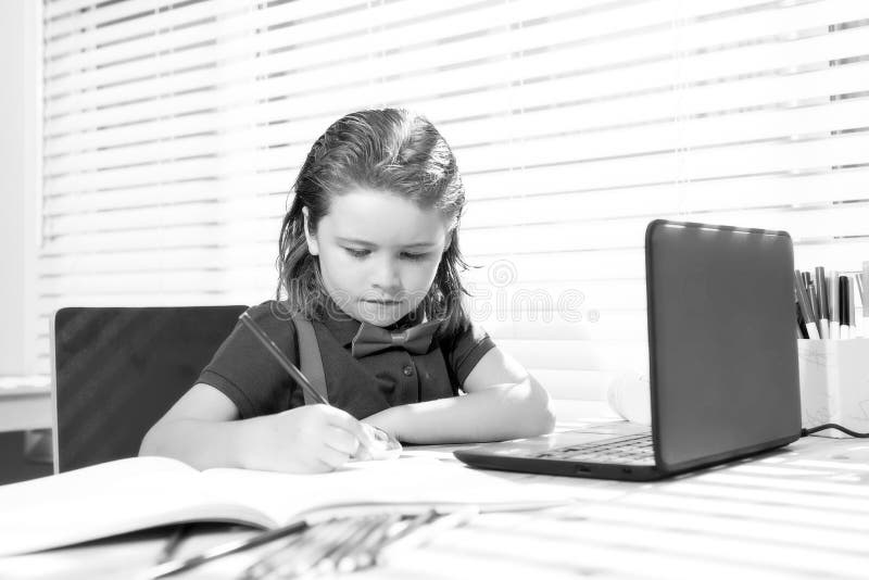 Smart School Boy Does Homework in School Class. Writes Text from Laptop ...
