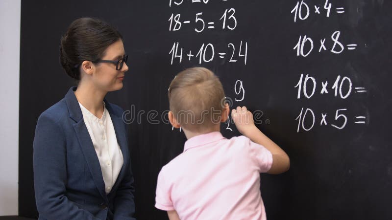 Smart Schoolboy Solving Math Exercises on Blackboard, Teacher Standing ...