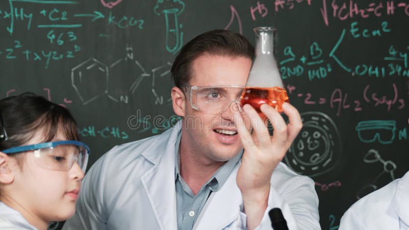 Teacher Holding Solution in Beaker while Student Doing Experiment ...