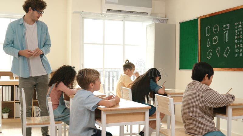 Smart Teacher Walking at Classroom while Looking at Student Homework ...