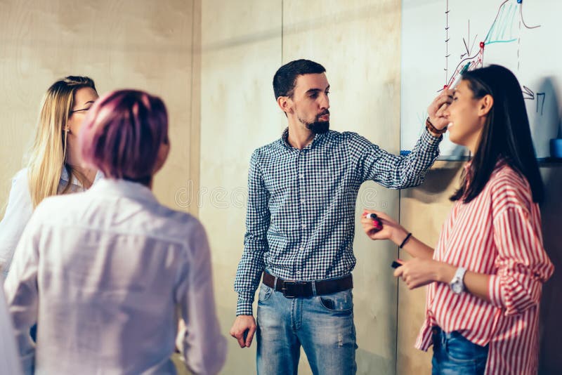 Smart Trainer Explaining and Showing Diagram on Plastic Board on Wall ...