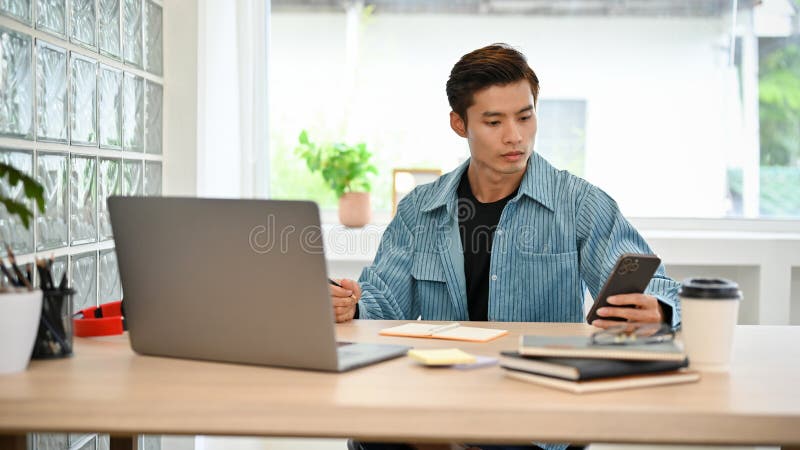 Smart Young Asian Businessman or Male Freelancer Using His Smartphone ... Smart Young Asian Businessman or Male Freelancer Using His Smartphone ...