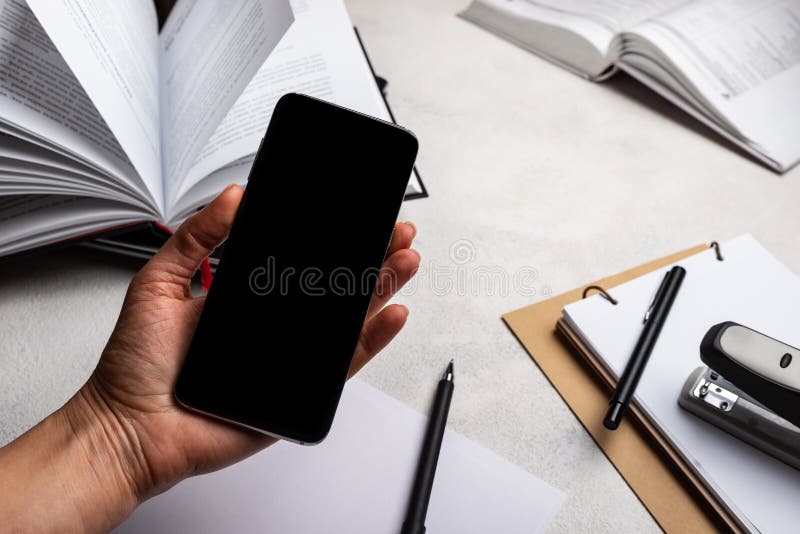 Smartphone with Blank Screen in Hand Above Workspace with Books. Stock ...