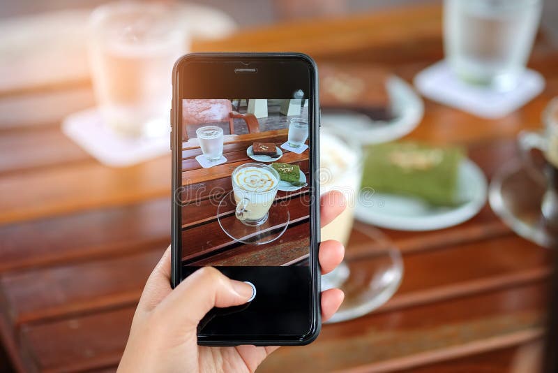 Smartphone in Hand with Latte Coffee and Cake on Table. Stock Image ...