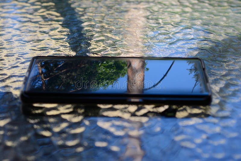 Smartphone with a Reflection of the Sky and Trees in the Screen, Lying ...