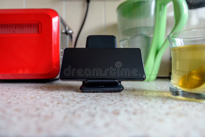 Smartphone Wireless Charging on Charging Stand Next To Tea Glass Cup on ...