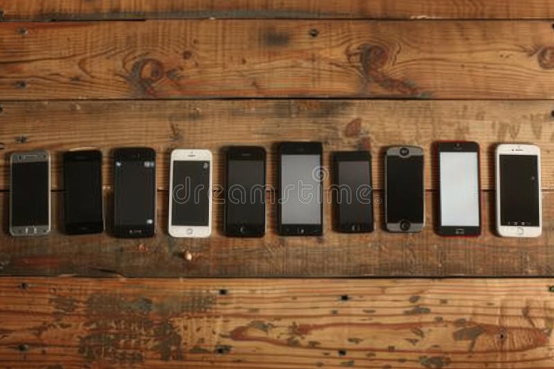 Smartphones from Different Generations Lined Up on a Wooden Table ...