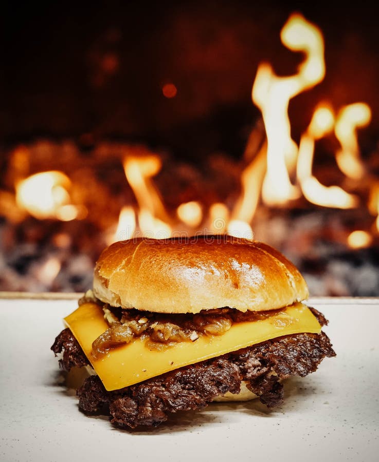 Smashed Cheeseburger on a Wooden Table in Front of a Fireplace. Stock ...
