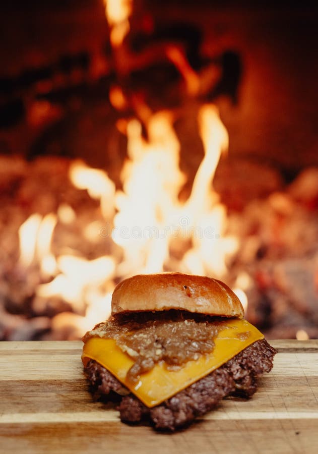 Smashed Cheeseburger on a Wooden Table in Front of a Fireplace. Stock ...