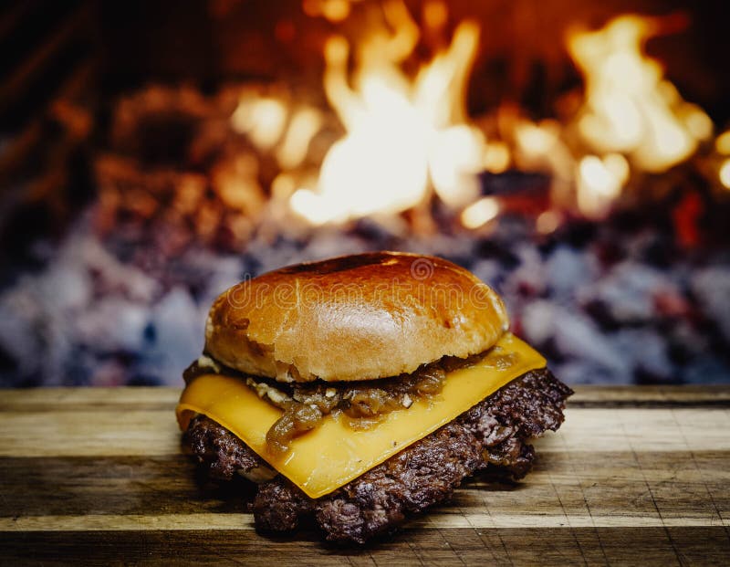 Smashed Cheeseburger on a Wooden Table in Front of a Fireplace. Stock ...