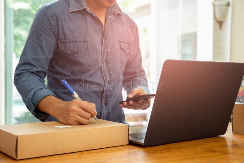 SME Business Man Looking Cell Phone and Writing Address on Parcel ...