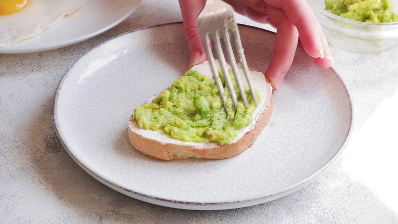 Smearing Mashed Avocado on Wheat Bread with Cream Cheese. Preparing ...